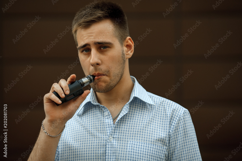 Vape man. Portrait of a handsome young white guy with modern haircut in ...