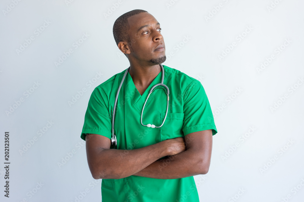 Portrait of pensive African American doctor standing with folded arms ...