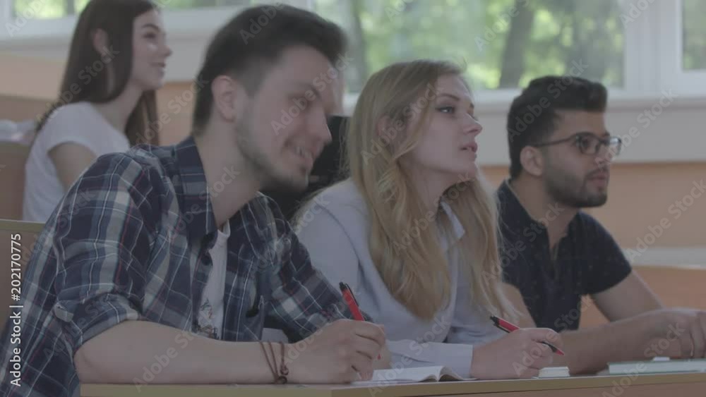 Positive students learning during university class in the big spacious ...