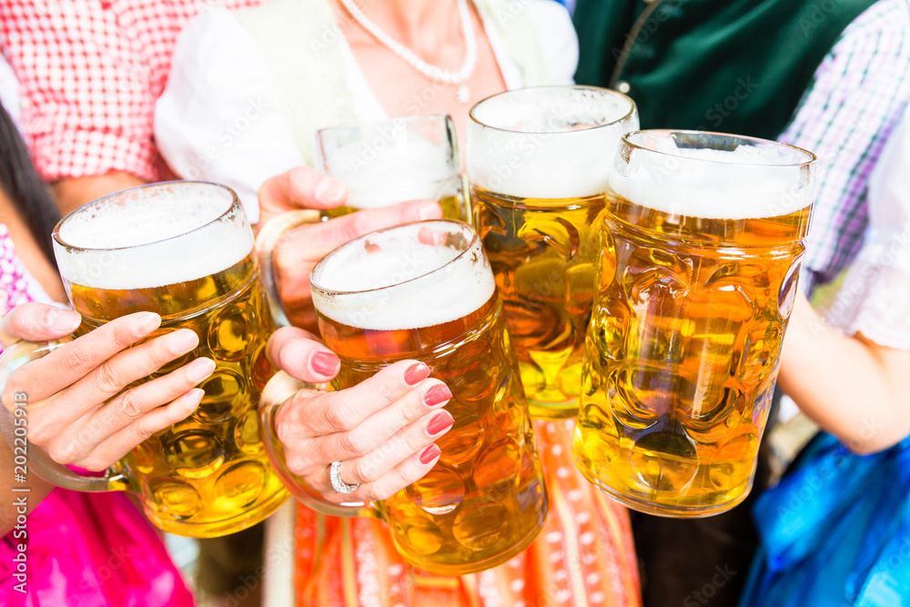 Anstoßen mit Bier in Maßkrügen im Biergarten Stock-Foto | Adobe Stock
