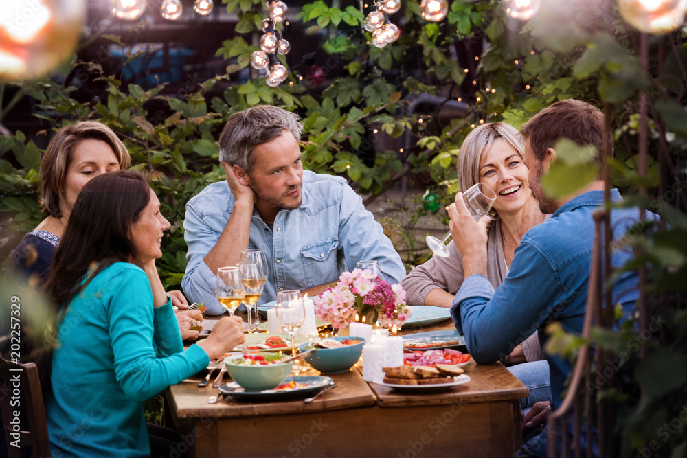 Group of friends gathered around a table in a garden on a summer ...