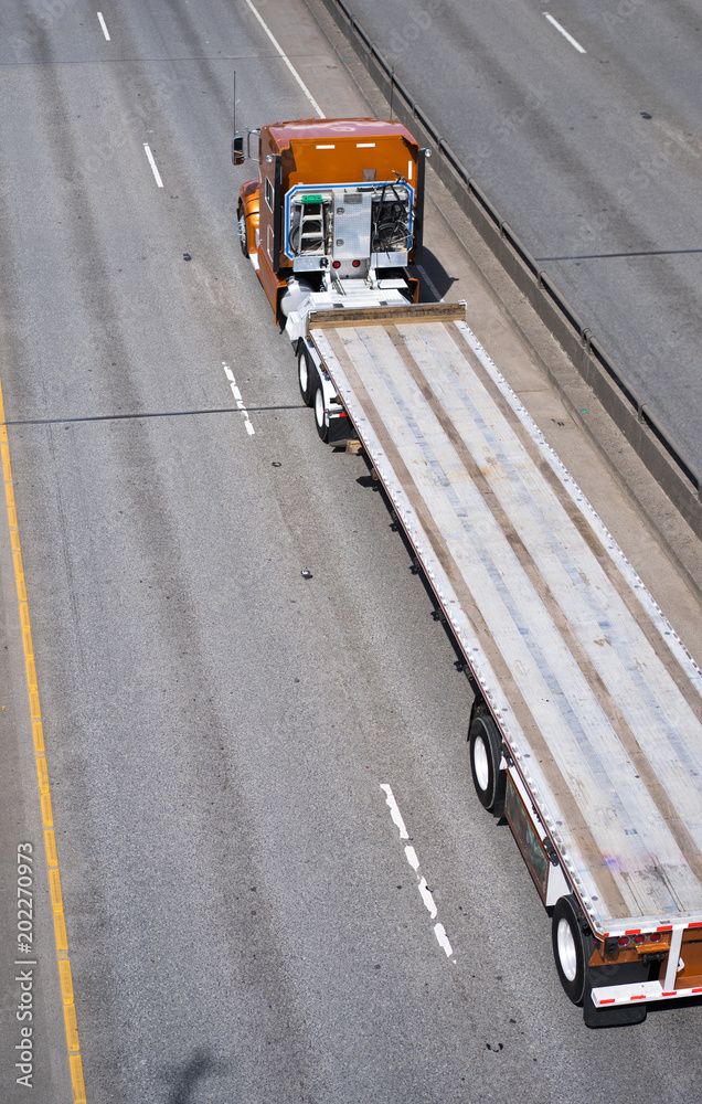 Brown bright big rig semi truck with empty flat bed semi trailer ...