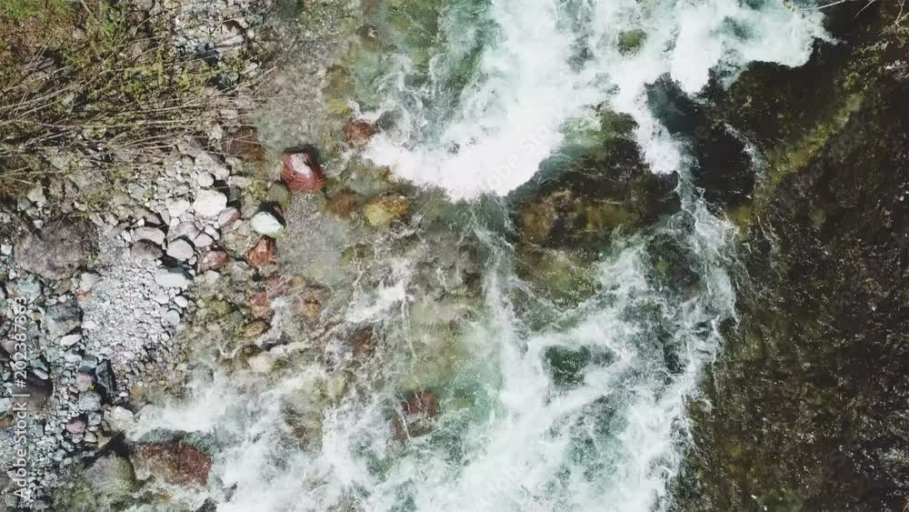 flying over a stream and waterfalls in mountains - aerial top view shot ...