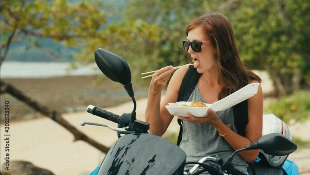 Woman Biker Eating Asian wok Noodle from Take away Box using chopsticks ...