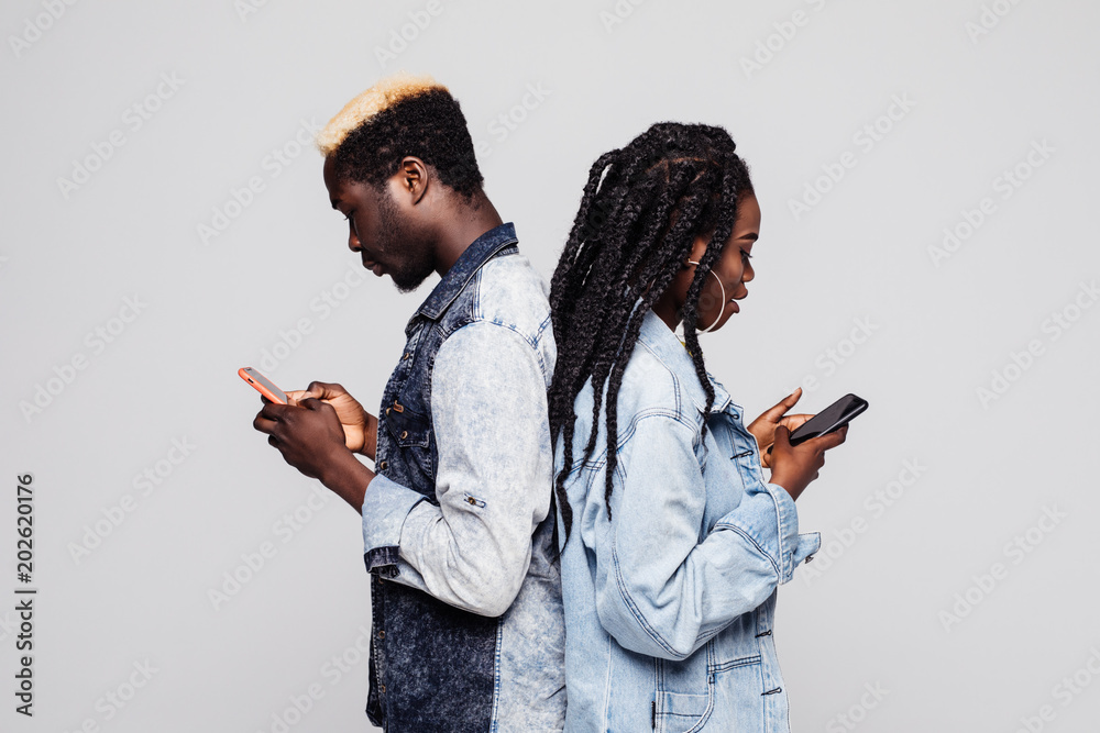 Time to use phones. Side portrait of african couple standing back to ...