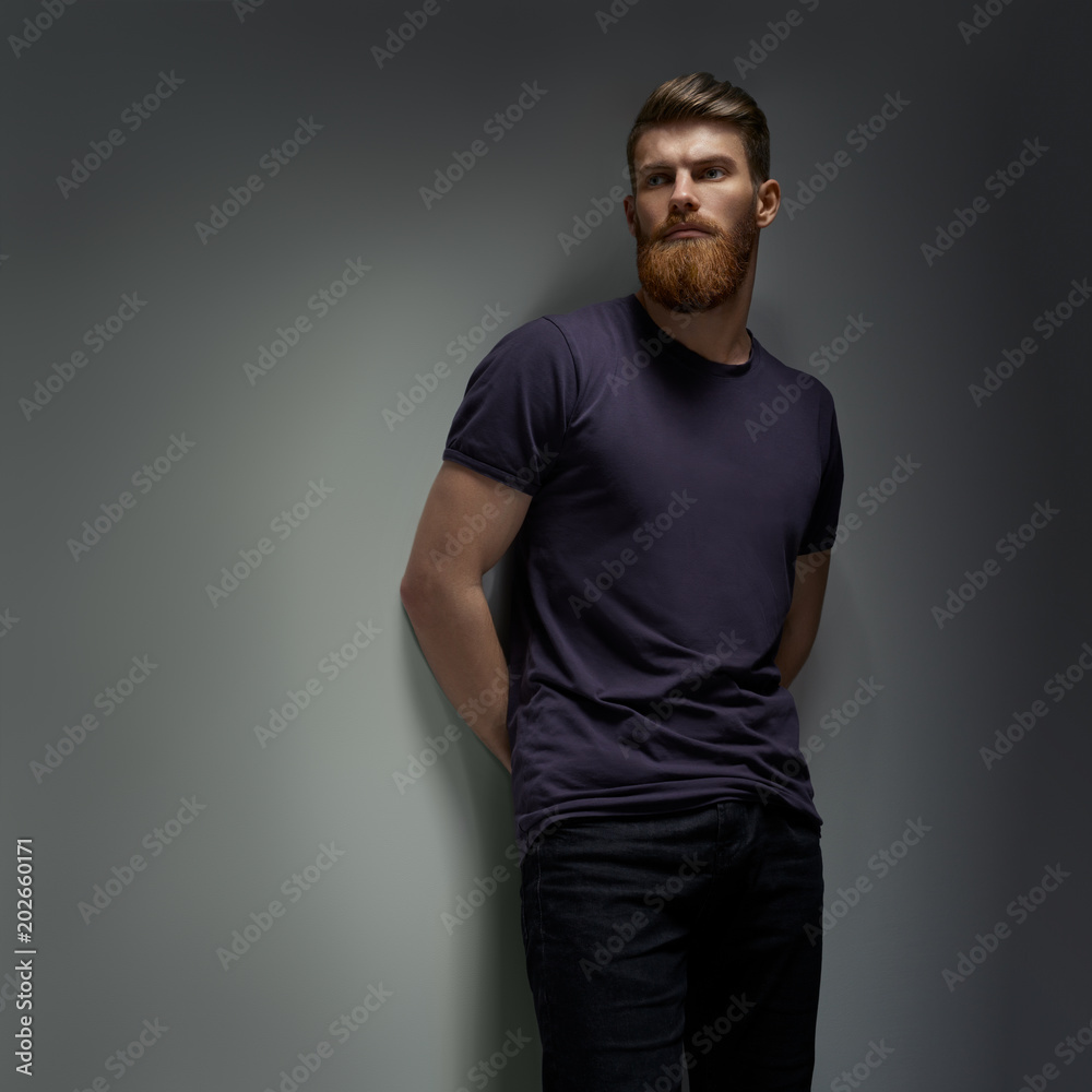 Young bearded man, model of fashion, looks into the distance wearing ...