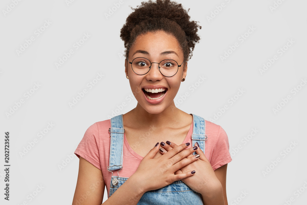 Overjoyed mixed race African female with happy expression, keeps hand ...