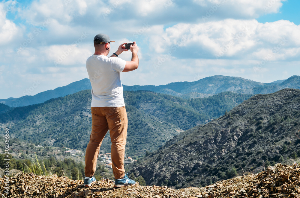 Hiking man making photo with his mobile phone camera.Young man standing ...