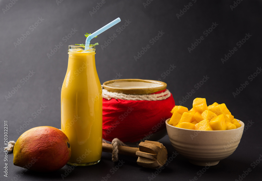 Mango Lassi or smoothie in big glass or small bottles with curd, cut ...