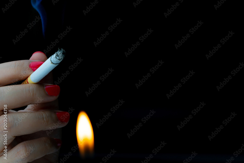 Sexy woman with red nail is smoking cigarette on dark background with ...