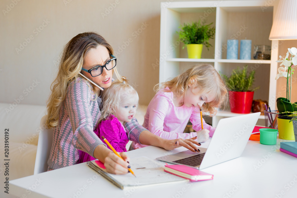 Busy woman trying to work while babysitting two kids Stock Photo ...