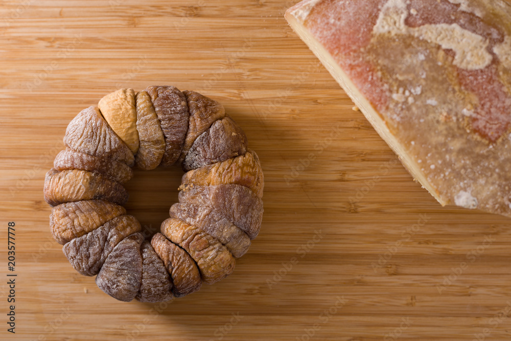 wheel of dried figs with a pecorino on top of wooden board on a white ...