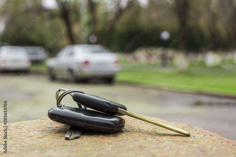 lost car keys on a marble slab, on a blurred car and park background ...