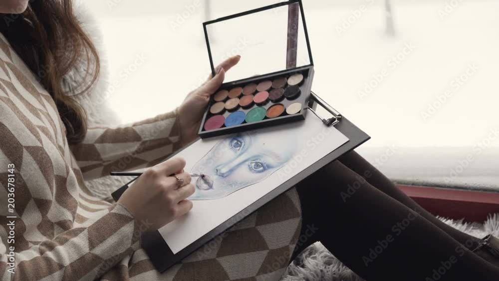 The artist on makeup and beauty sits on the window sill near window and ...