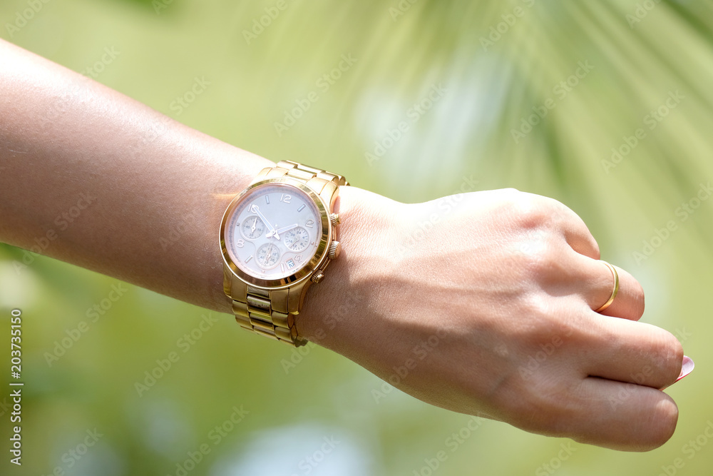woman's arm wore a gold watch on the natural wrist.Natural background ...
