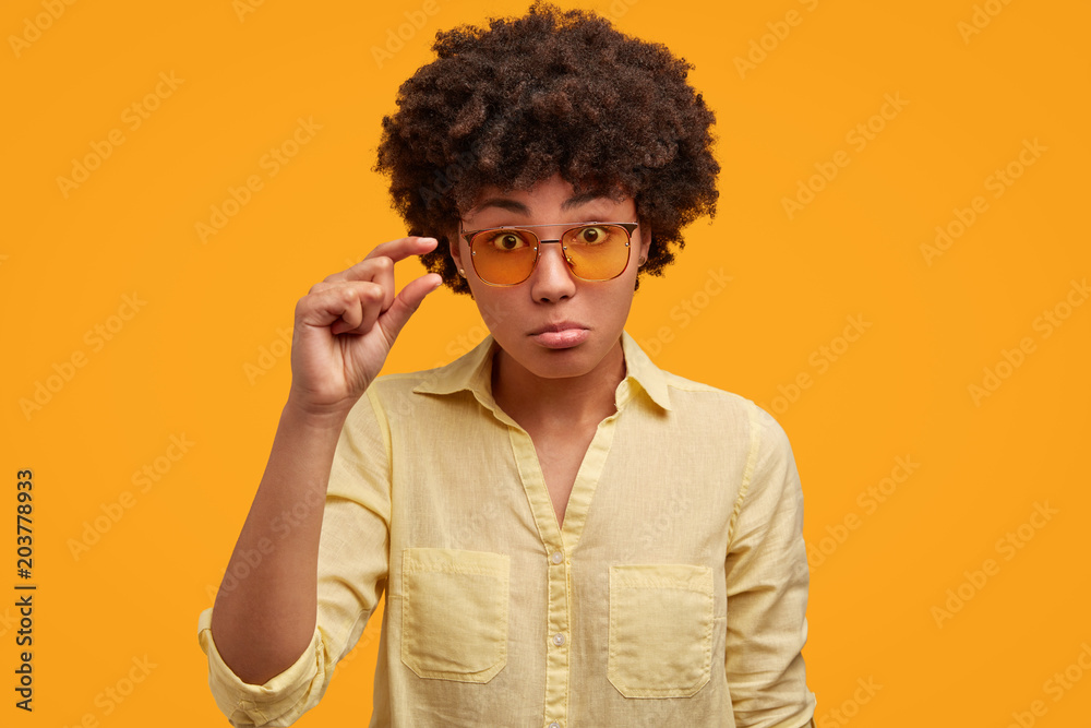 Beautiful dark skinned woman shows something tiny, has serious ...