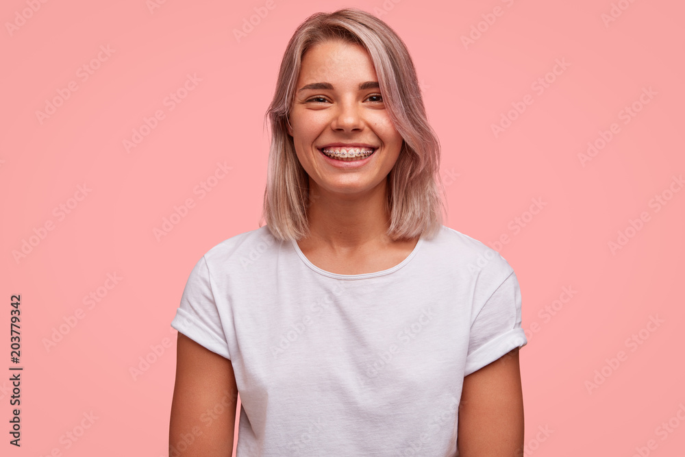 Portrait of happy female with broad smile, wears brackets on teeth and ...