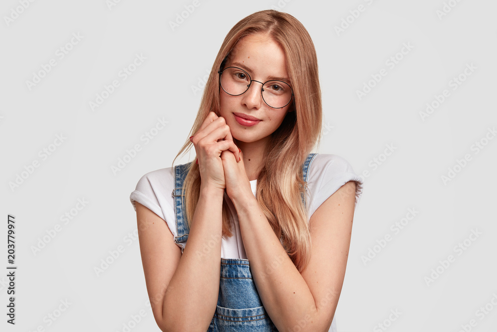Delighted Caucasian woman with attractive look, keeps hands together ...