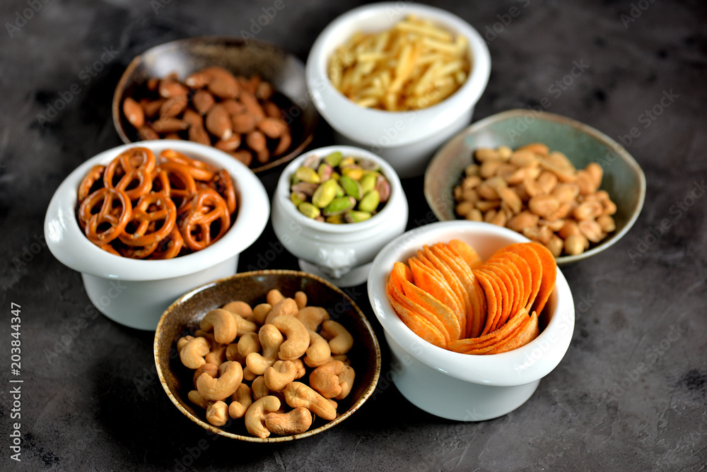 Different kinds of snacks - chips, salted peanuts, cashews, almonds and ...