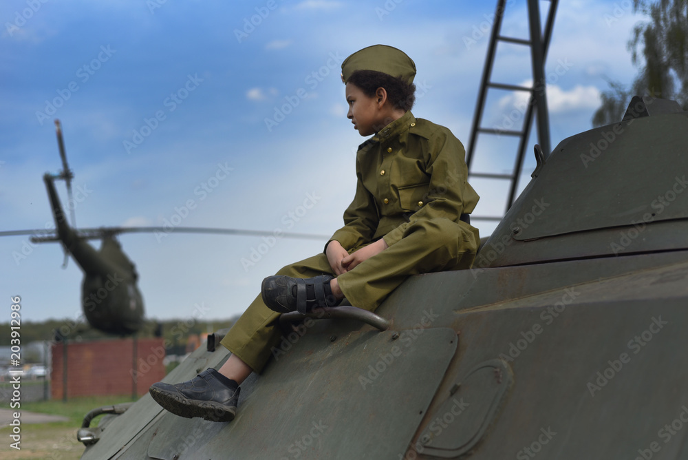 Boy in the military uniform on the tank of time of Second World War ...