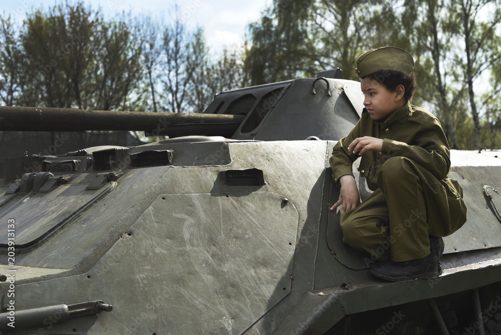 Boy in the military uniform on the tank of time of Second World War ...