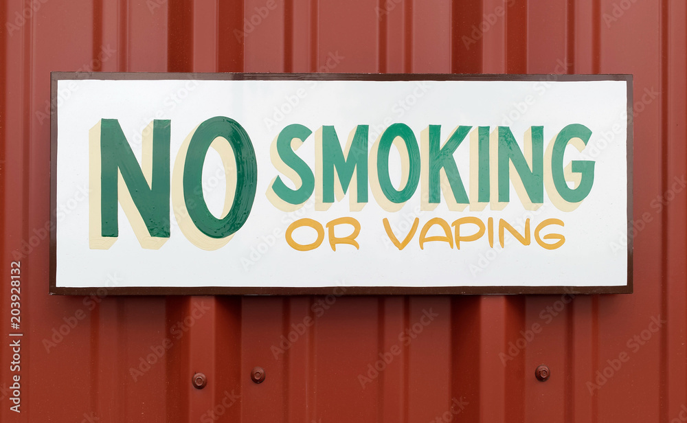 NO SMOKING NO VAPING sign attached to exterior metal building wall ...