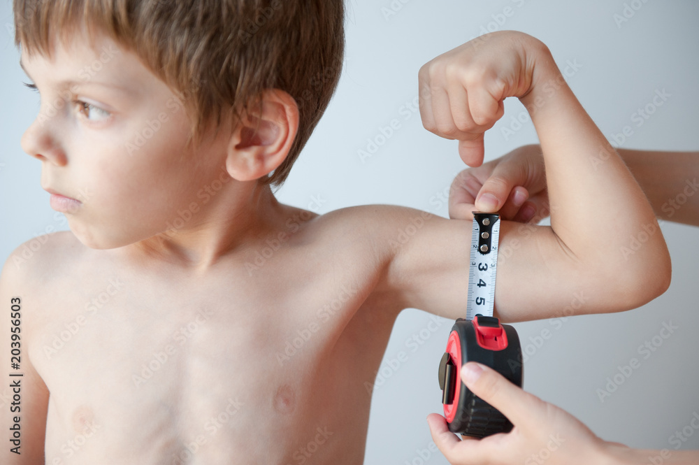 child measures healthy strong little boy muscles with measuring tape ...