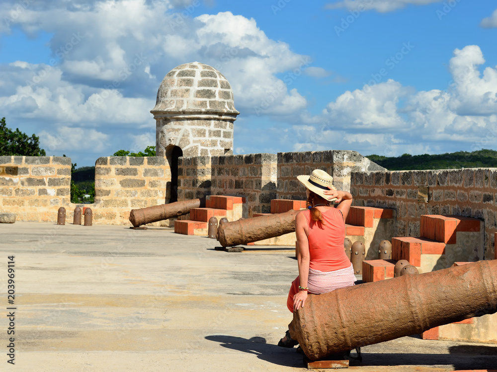 The tourist touring the Jagua fort is sitting on the ancient cannon ...