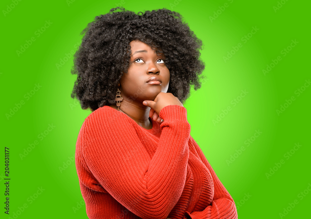 Beautiful african woman thinking and looking up expressing doubt and ...