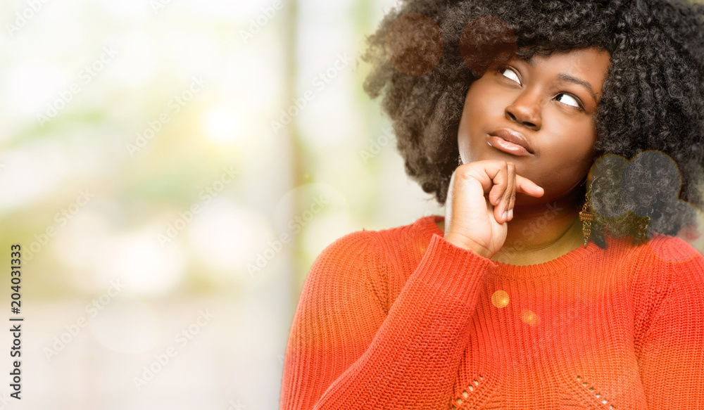 Beautiful african woman thinking and looking up expressing doubt and ...