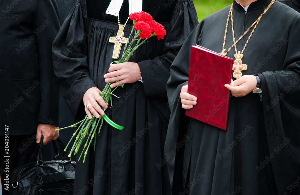 Two priests standing next to each other on the ceremony. One of them is ...