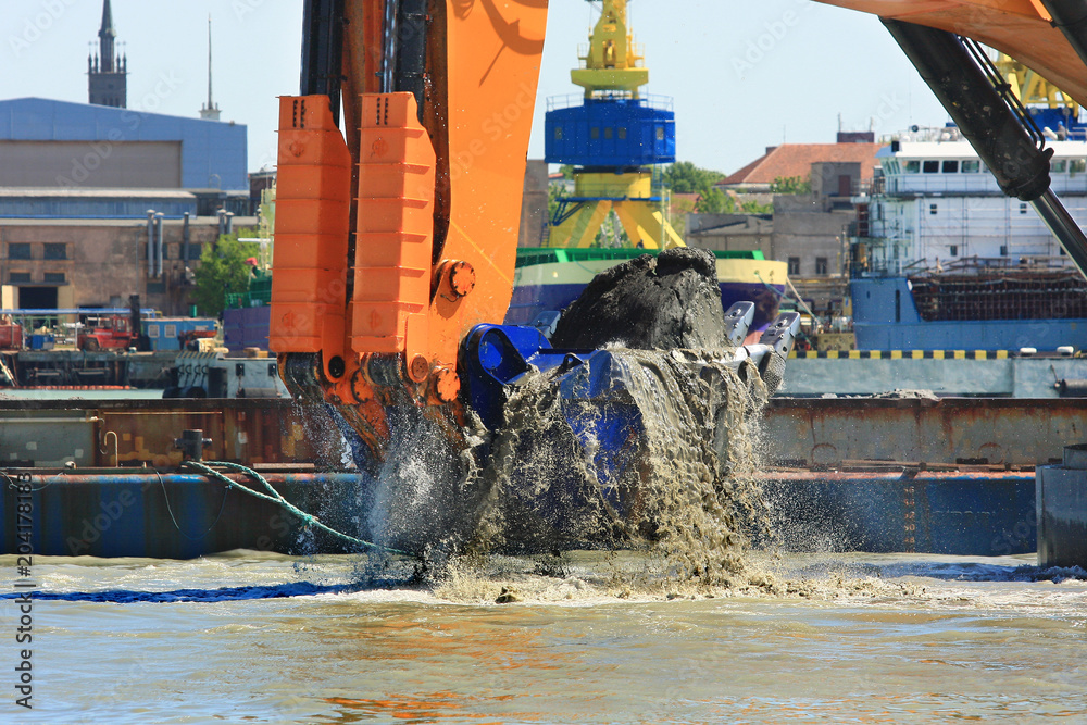 Floating dredge deepens the fairway for large container ships at the ...