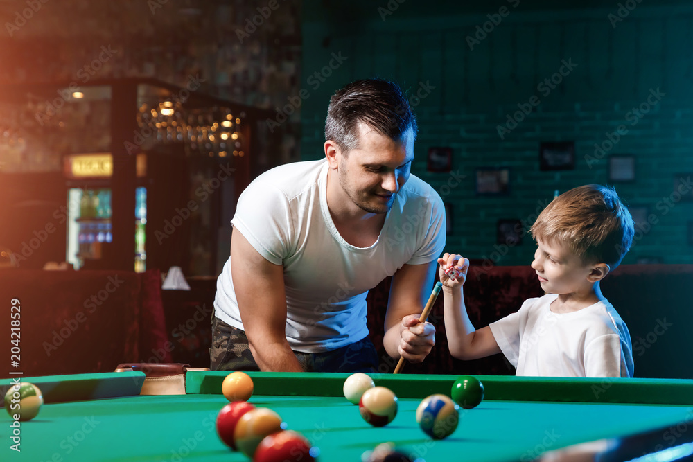 Father and son play billiards. The father teaches his son to play ...