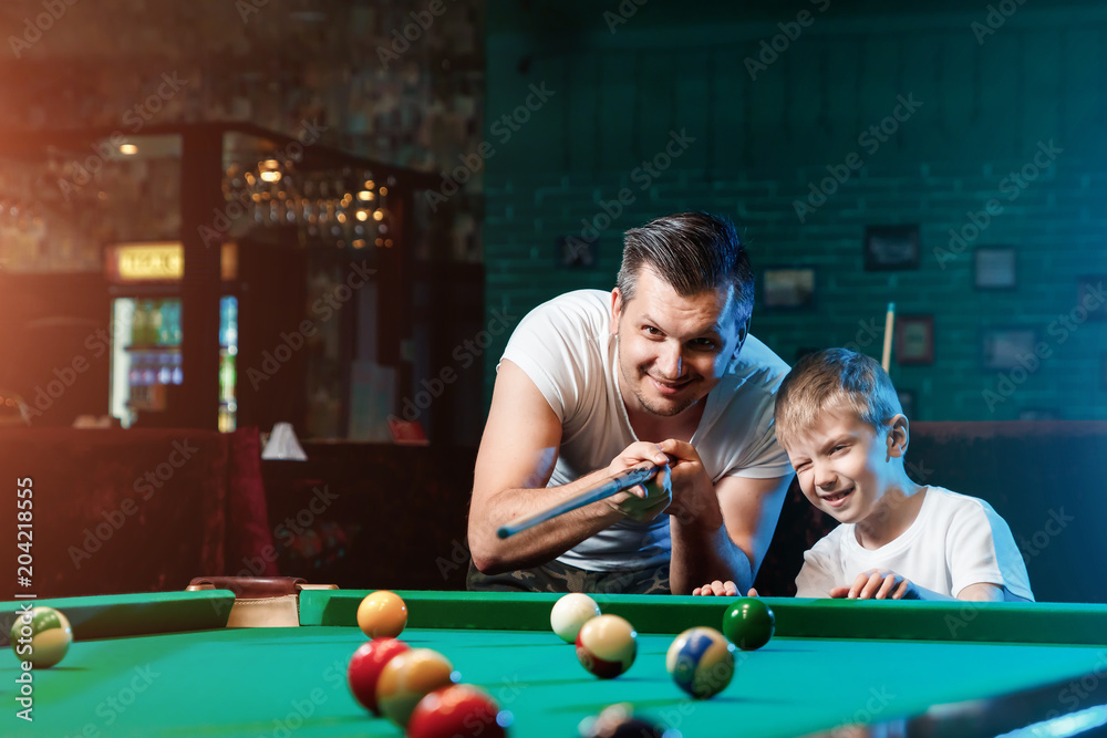 Father and son play billiards. The father teaches his son to play ...