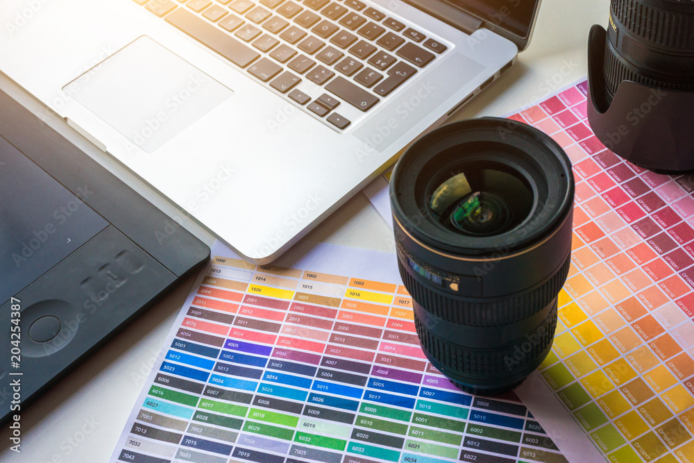 Graphist designer photographer desk with color chart, lens, laptop and ...