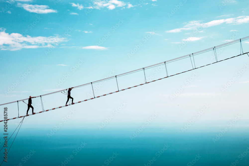 Young woman crossing the chasm on the rope bridge. Ai-Petri, Crimea ...