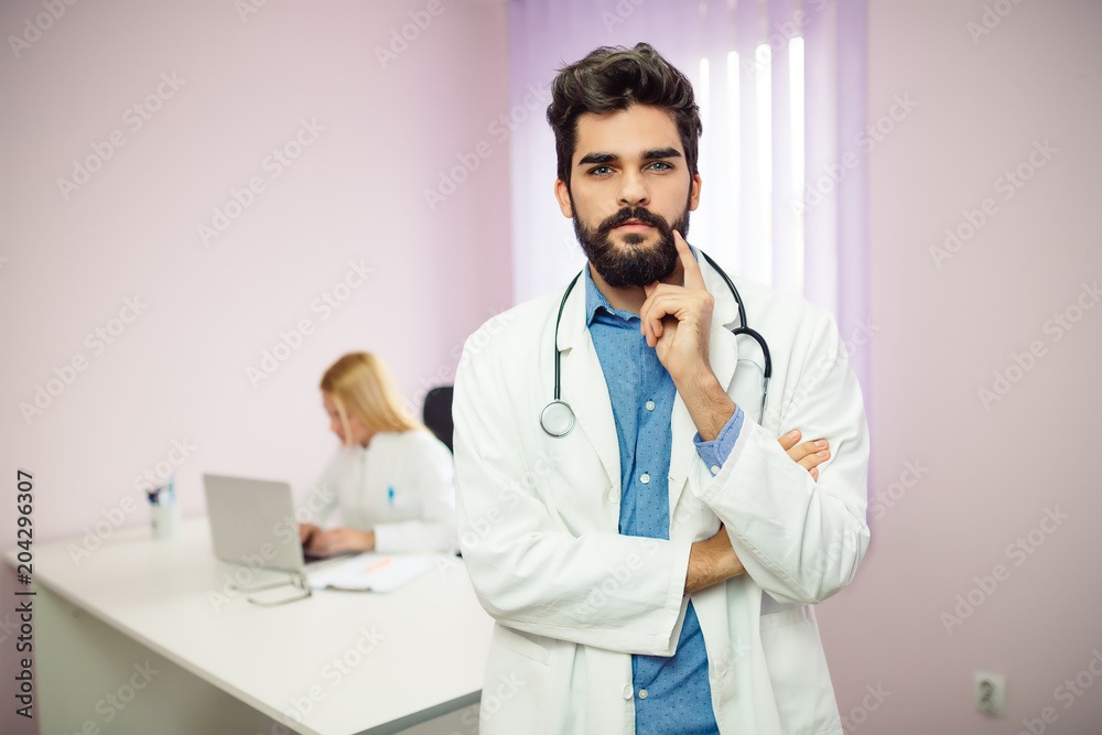 Confident male doctor standing with crossed arms at the medical office ...