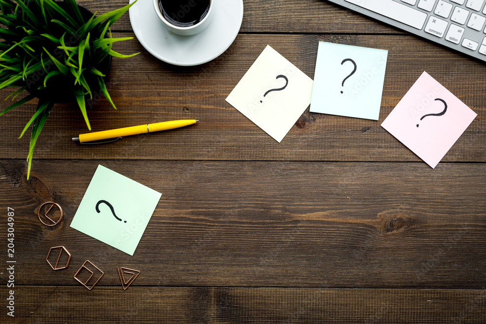 Question mark on sticky notes on office desk on dark wooden background ...