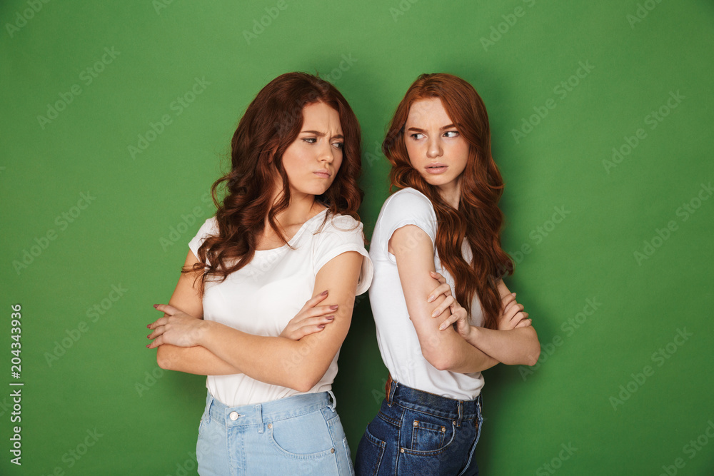 Two displeased girls 20s with ginger hair in casual wear standing back ...
