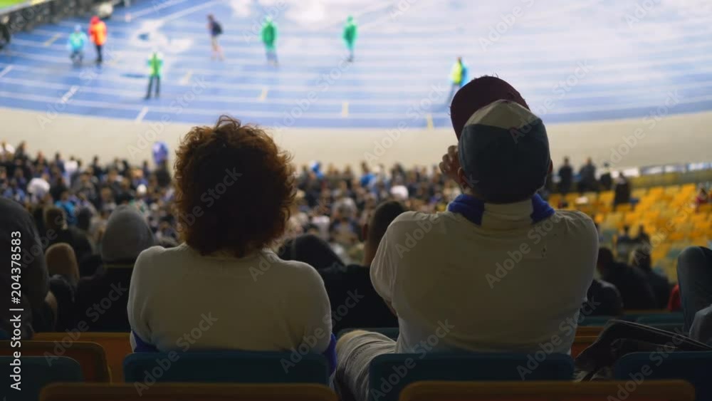 Man and woman watching football (soccer) game at stadium, clapping ...