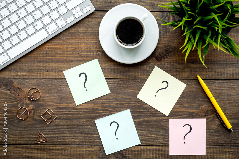Question mark on sticky notes on office desk on dark wooden background ...