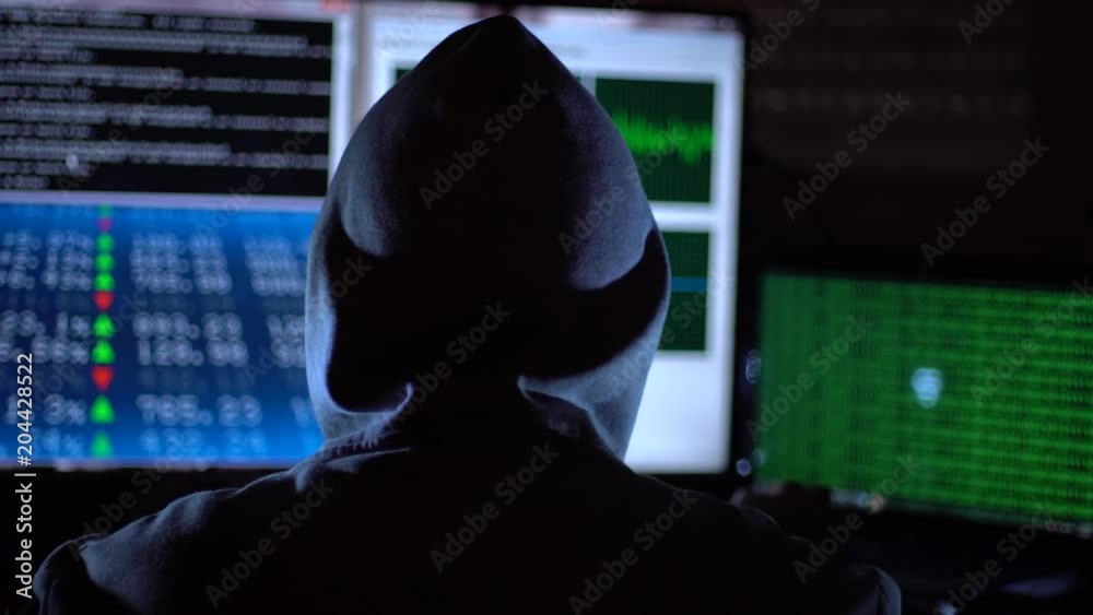 Hooded hacker coding security data on a computer in dark room. Male ...