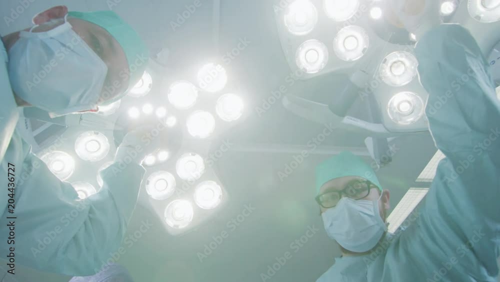 Low Angle Shot POV Patient View: Two Professional Surgeons Turning on ...