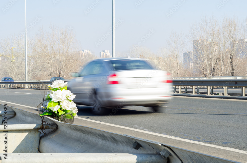 Artificial white roses flowers on the site of a car crash traffic ...