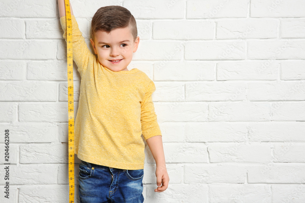Little boy measuring his height on brick wall background Stock Photo ...