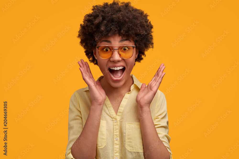 Optimistic dark skinned woman has overjoyed expression, keeps mouth ...