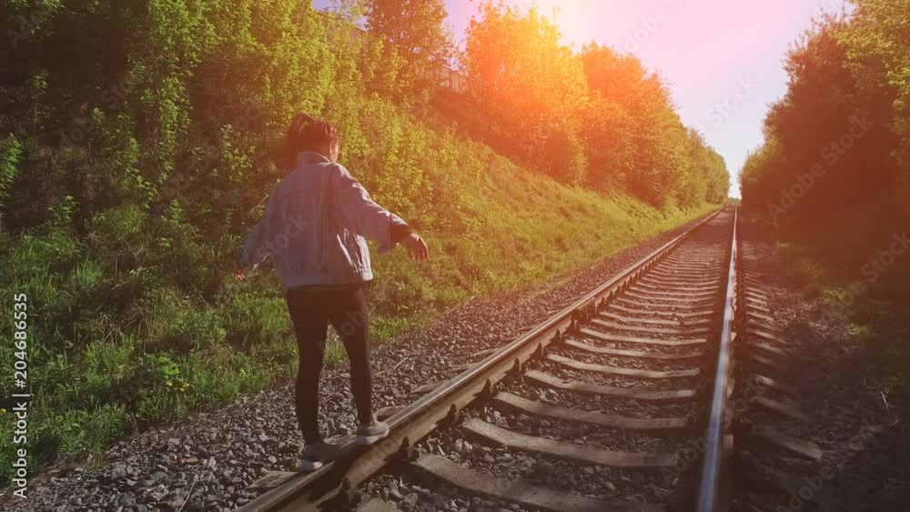 Young girl are walking on the railways - one of rail. She looking ...