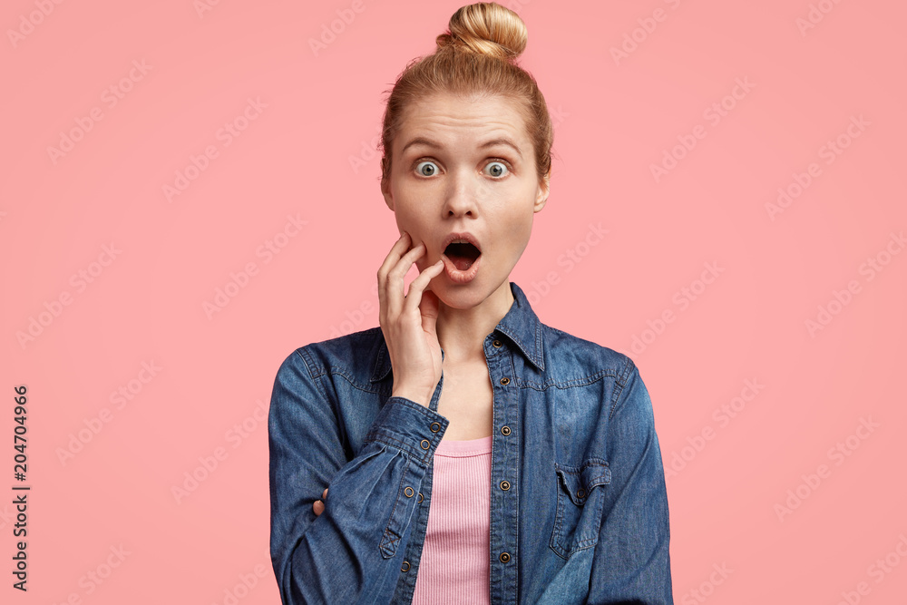 Stupefied blonde woman looks scared and frightened, keeps mouth wide ...
