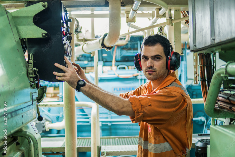Marine engineer inspecting ship's engine in engine control room ECR ...