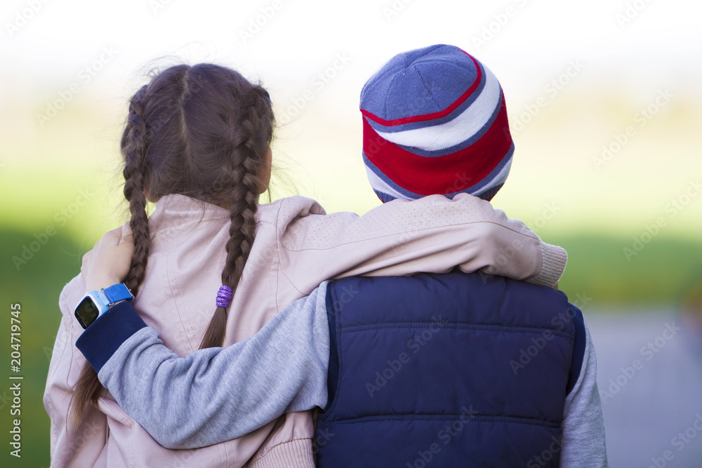 Half-length back view of two children, girl with long dark braids and ...